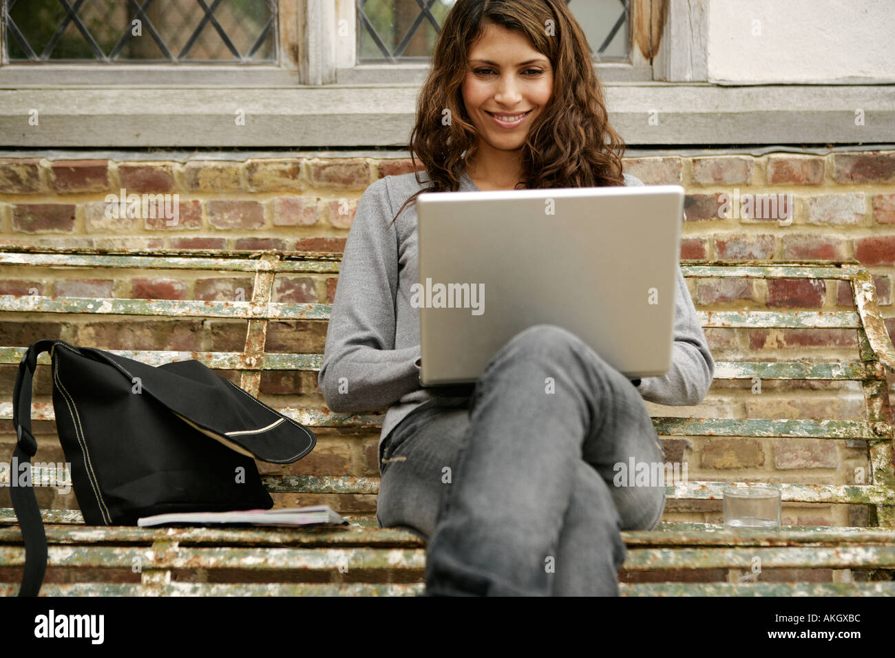 Woman sitting on bench using laptop computer Stock Photo - Alamy