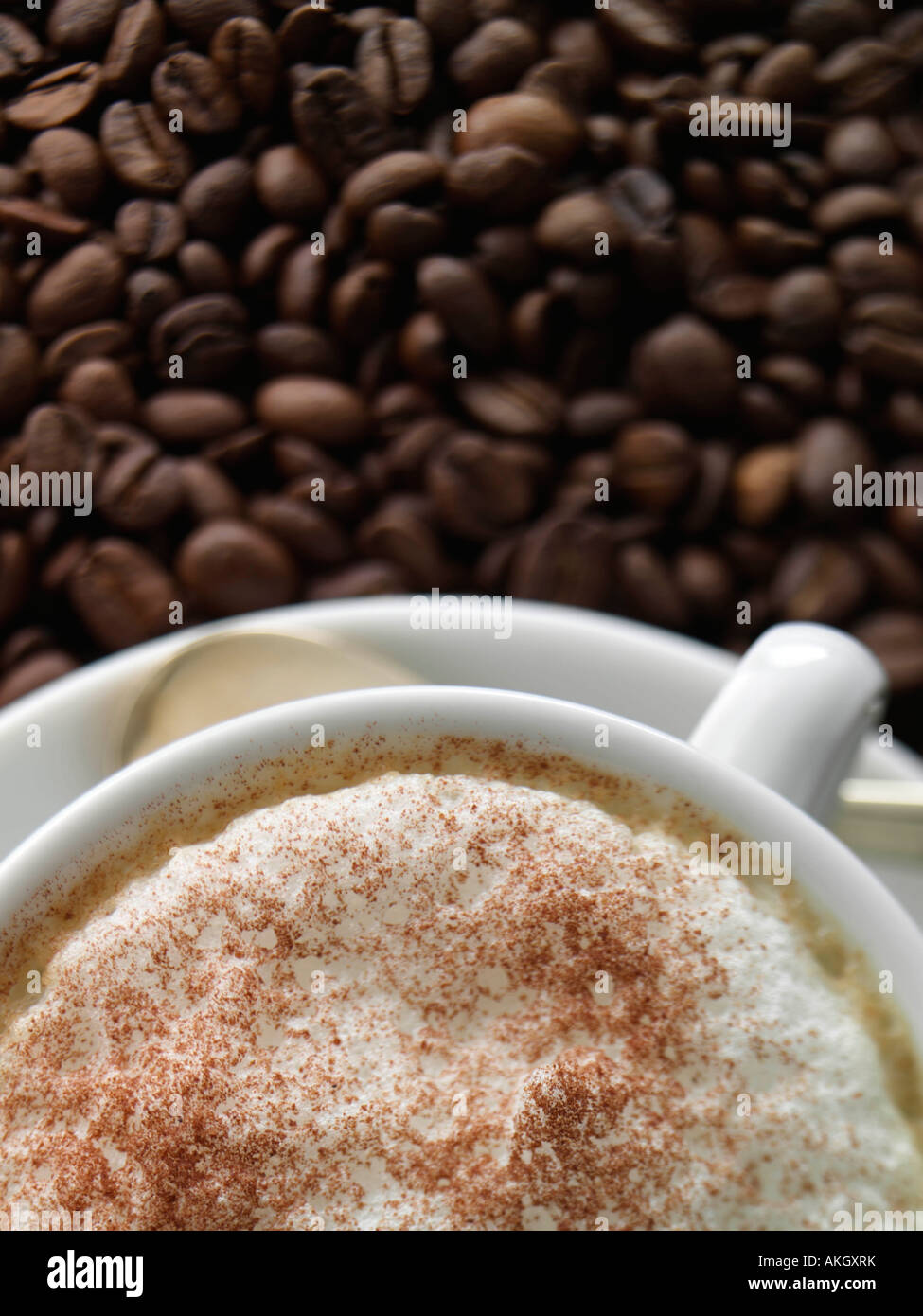 A cup and saucer of frothy cappuccino coffee and coffee beans editorial ...
