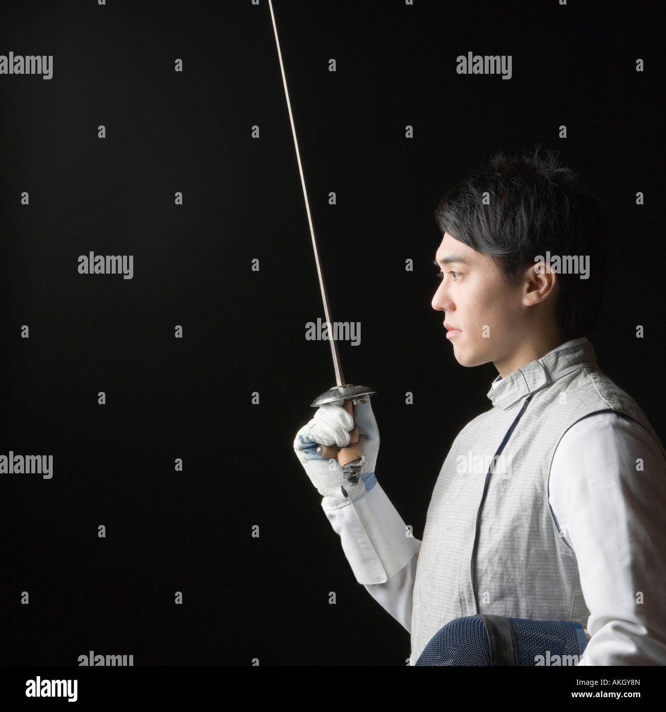 Side profile of a male fencer holding a fencing foil and a fencing mask ...