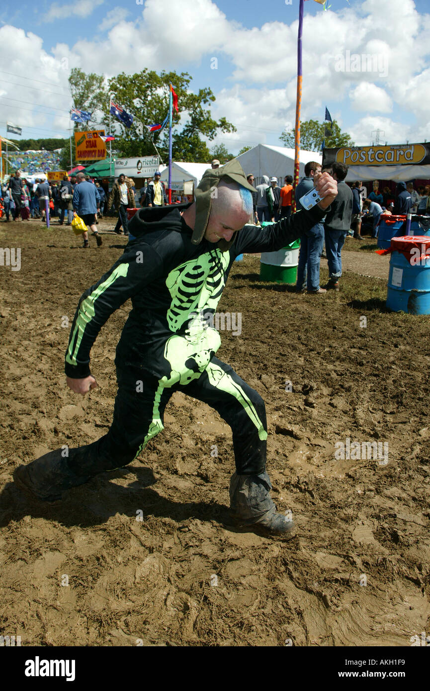 A young man dressed in a fancy dress dancing in the mud Glastonbury ...