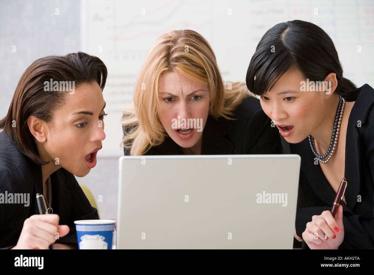 Three young women looking shocked at opened laptop Stock Photo - Alamy