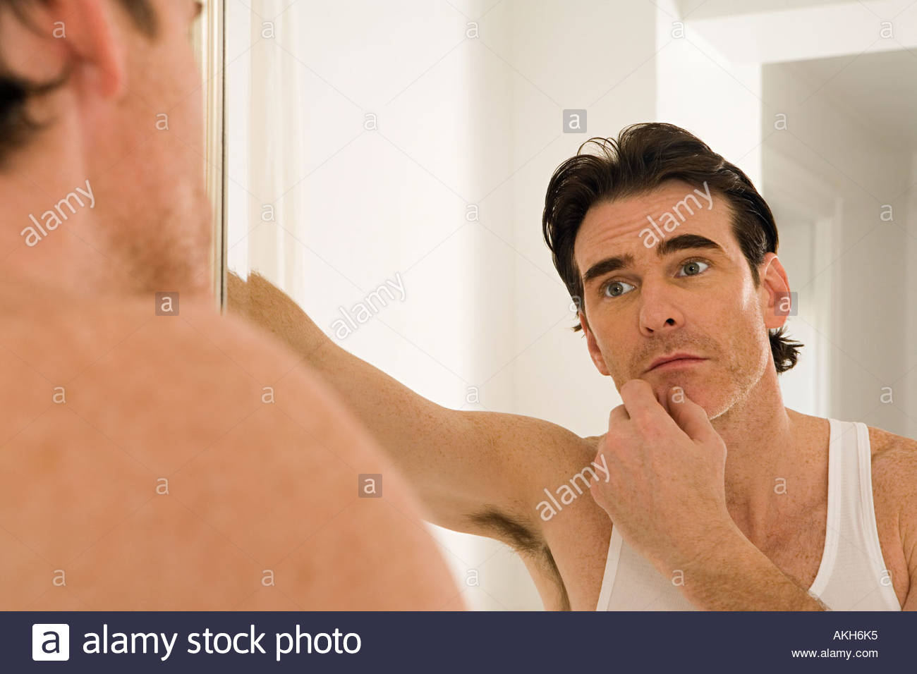 Man In The Bathroom Looking At Himself In The Mirror Stock Photos & Man ...
