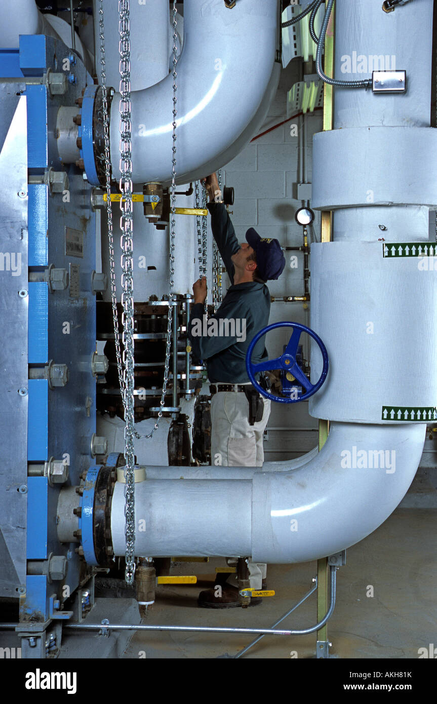 Worker and pipes for boiler in climate control system in new skyscraper ...