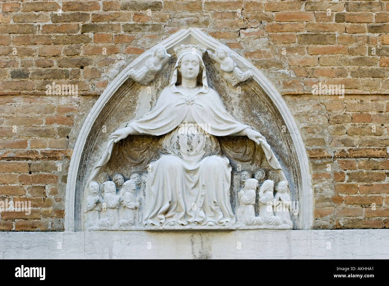 Carving of the Virgin Mary with angels and kneeling praying monks in a ...