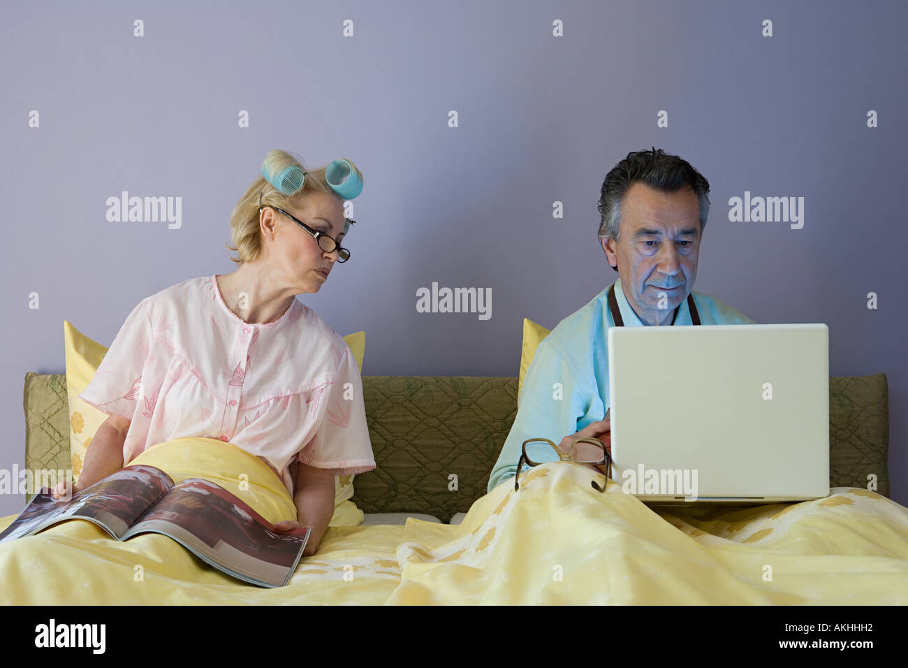 Couple in bed with laptop and magazine Stock Photo - Alamy