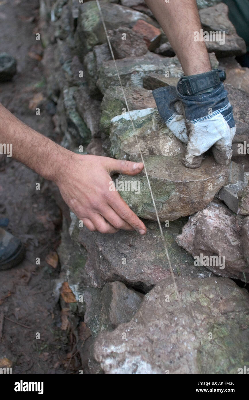 Dry stone walling. Placing stones using a level as a guide Stock Photo ...