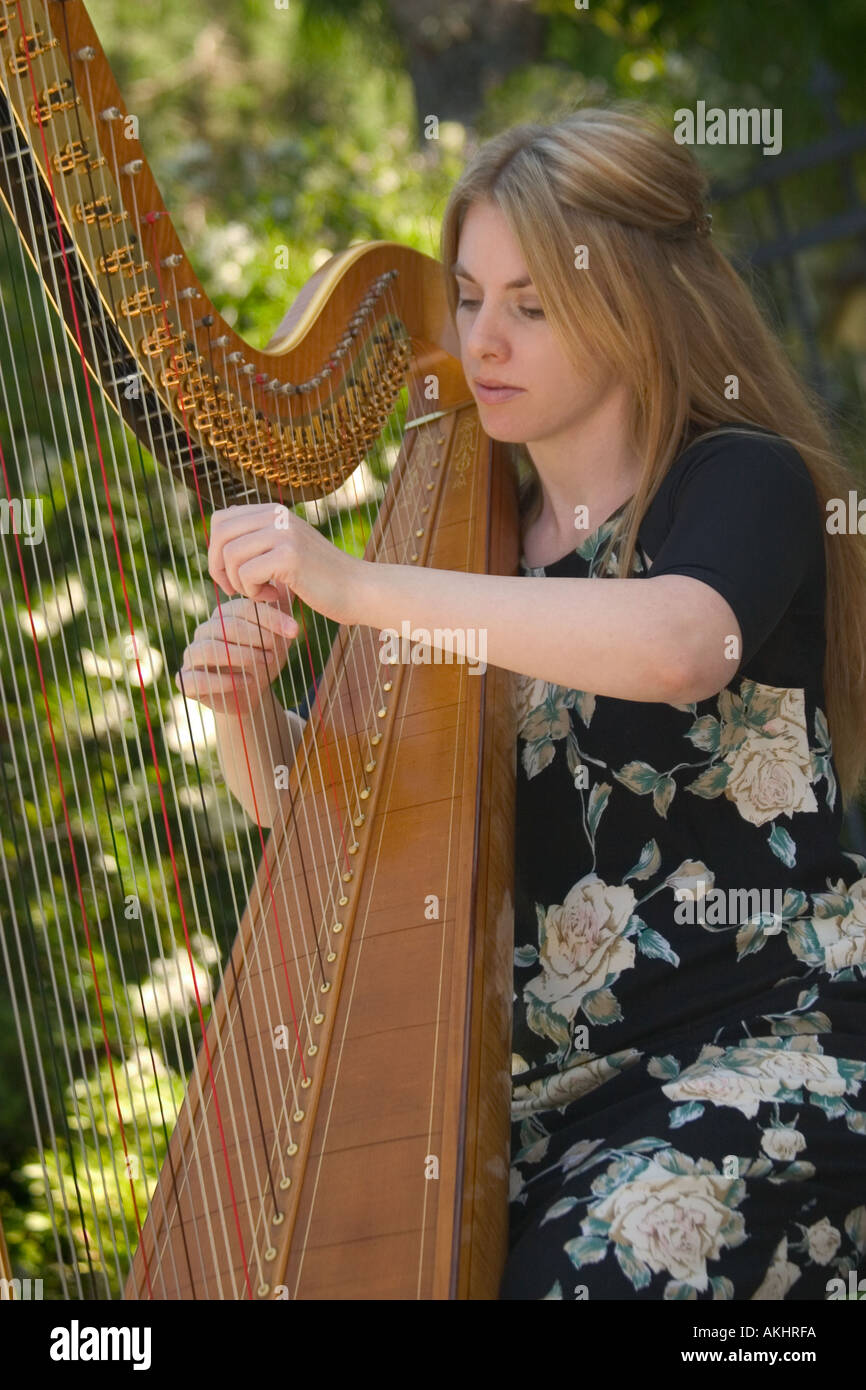 A pretty young harpist plays the harp in a summer garden Stock Photo ...