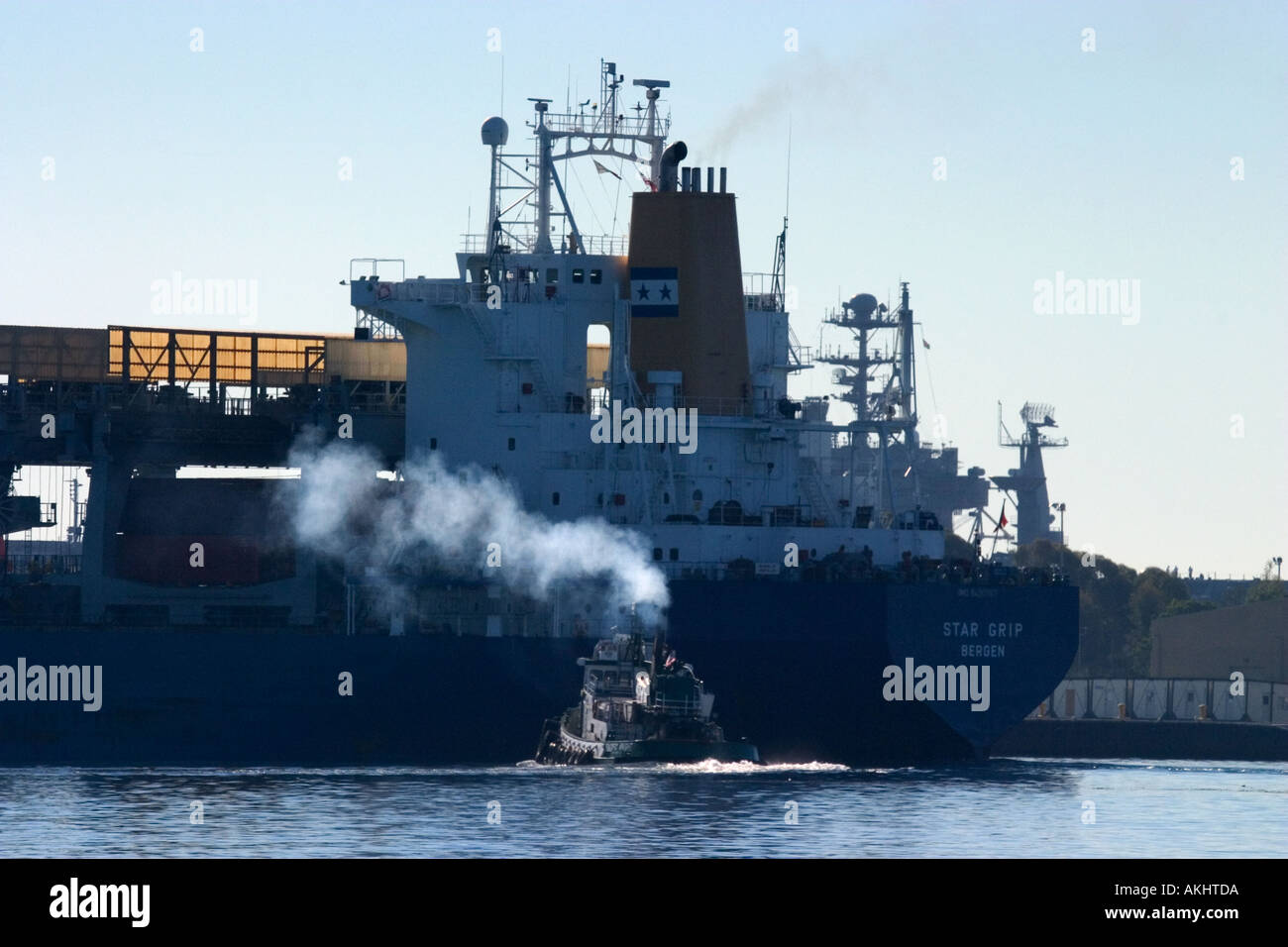 A tugboat pushing a container ship into port Stock Photo - Alamy