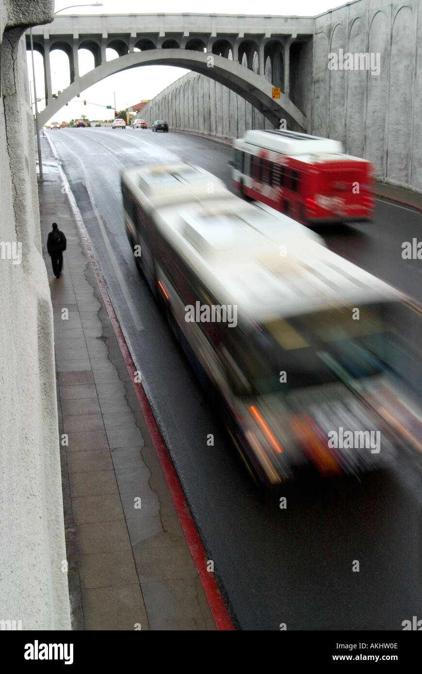Two busses travelling in opposite directions as a pedestrian walks ...