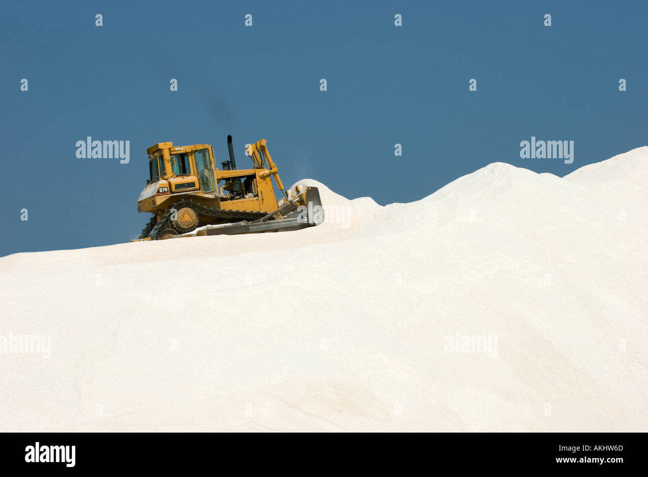 A yellow bulldozer pushes road salt uphill Stock Photo - Alamy