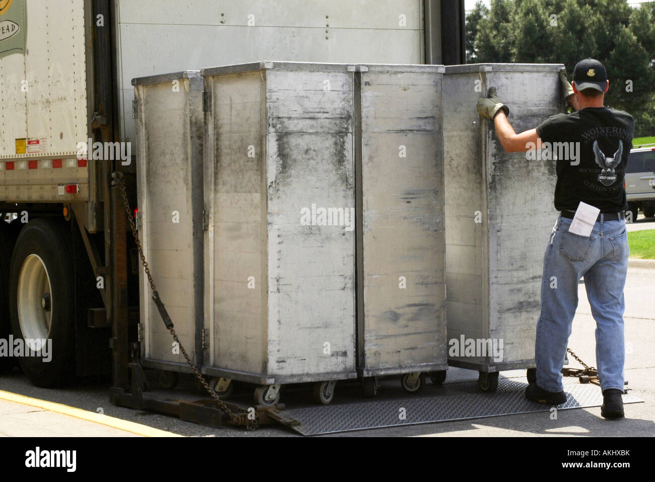 Truck driver man handling metal containers on a delivery to a retail ...