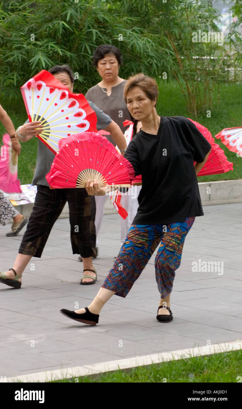 Chinese women practice Tai Chi with fans in a city park along the Jin ...
