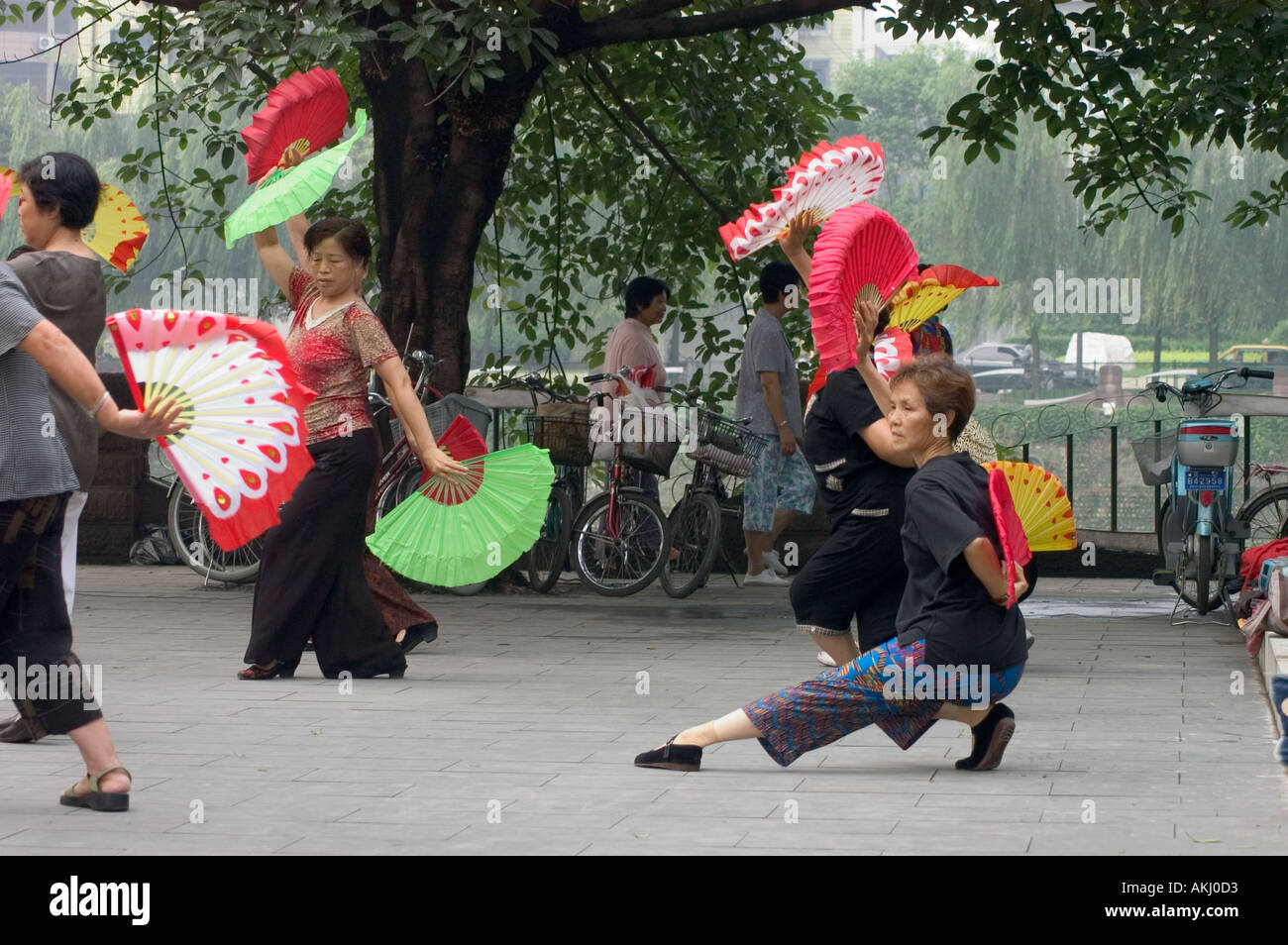 Chinese women practice Tai Chi with fans in a city park along the Jin ...