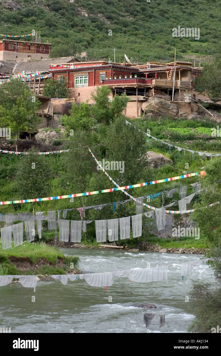 Prayer flags cross a river below a Tibetan Buddhist Temple in Derge ...