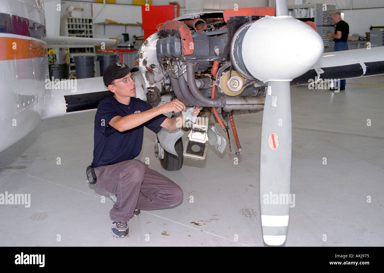 Airline mechanic works on a twin engine airplane Stock Photo - Alamy