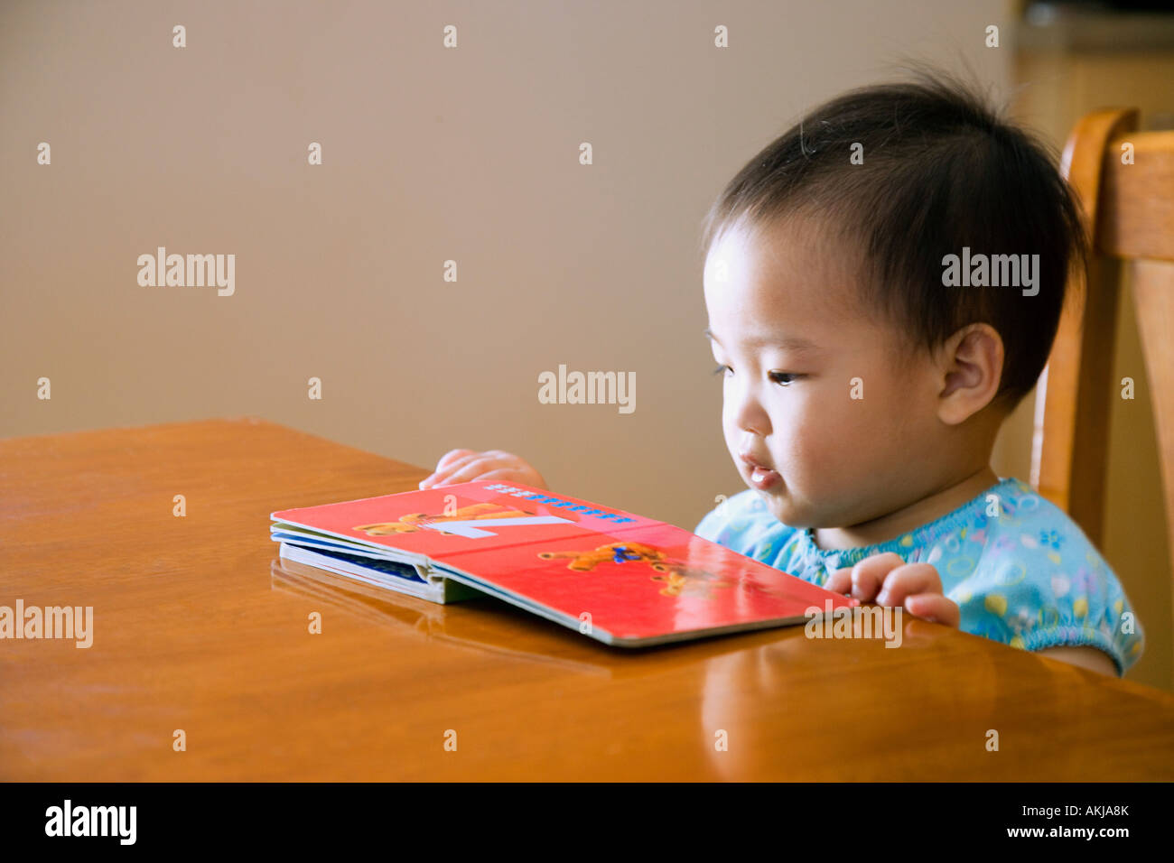 Toddler looking at a book Stock Photo - Alamy