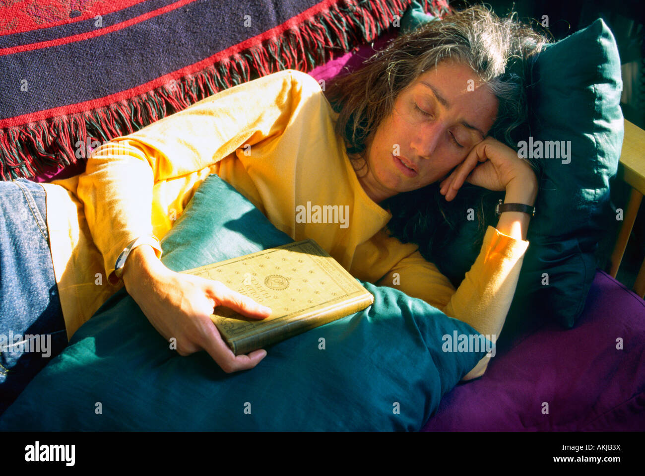 A woman holds a book as she naps in the sun Stock Photo - Alamy