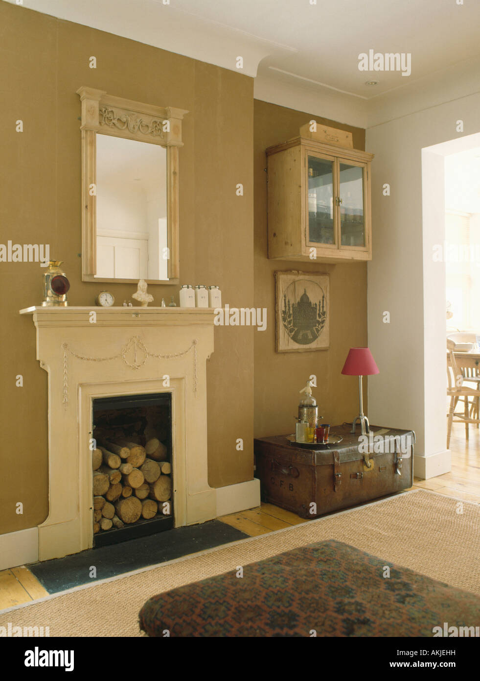 Logs in cream fireplace in pale brown living room with old leather ...