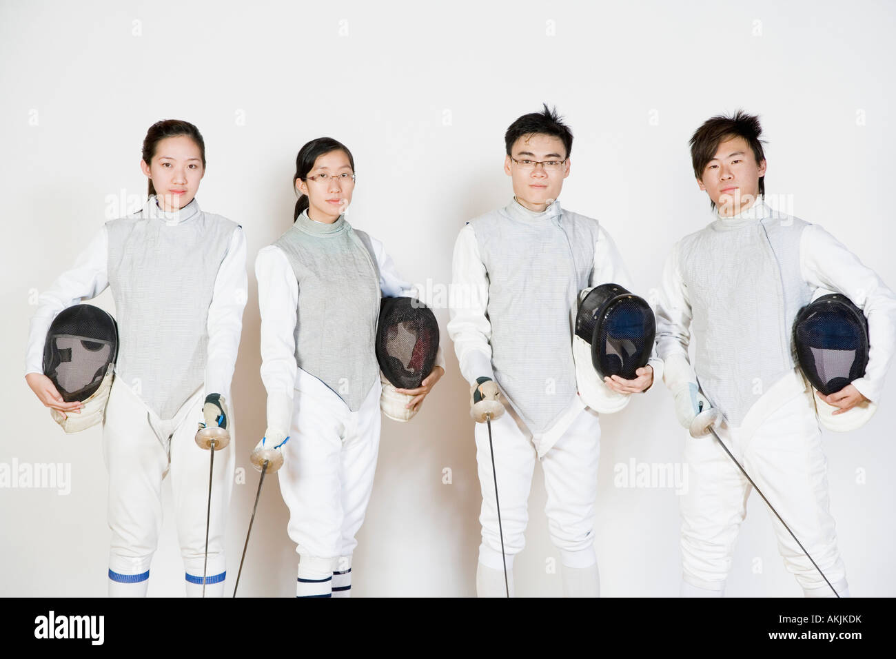 Portrait of two male and two female fencers holding fencing masks with ...