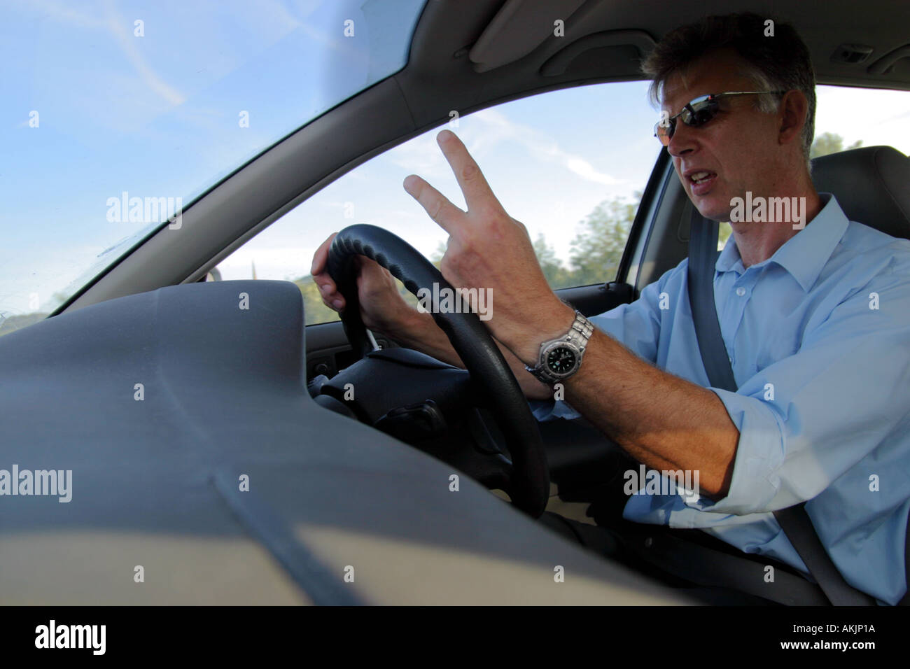 Angry middle aged male driver giving the V sign in a moment of road ...