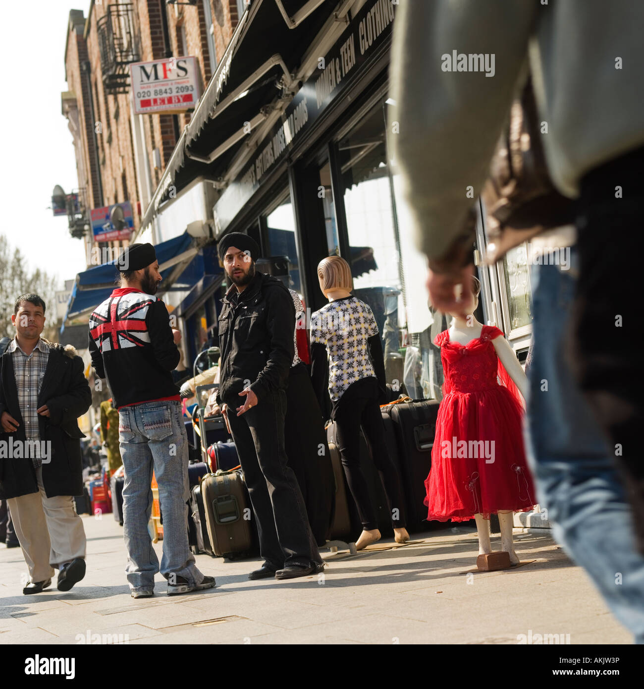 Sikh shopkeeper talking outside store high street Southall West London ...