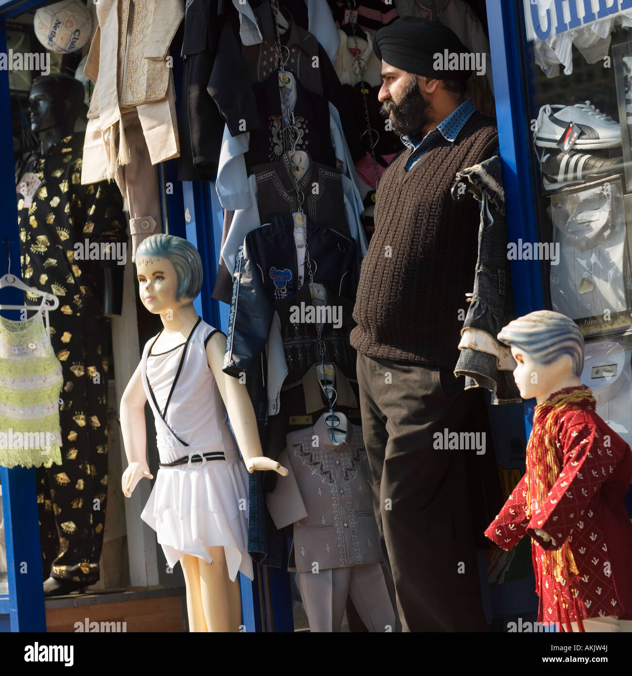 Sikh shopkeeper surrounded by mannequins of children at doorway of his ...