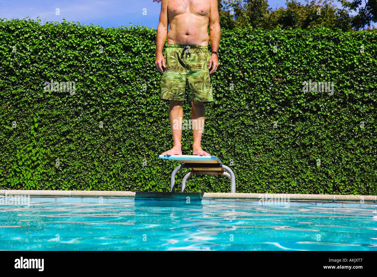 Man standing on swimming pool diving board Stock Photo - Alamy