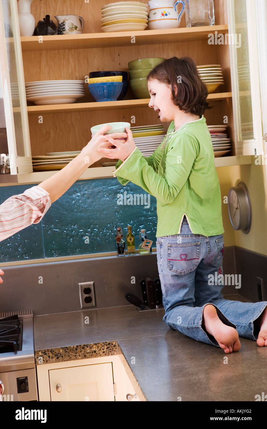 Girl kneeling on kitchen counter with dishes Stock Photo - Alamy