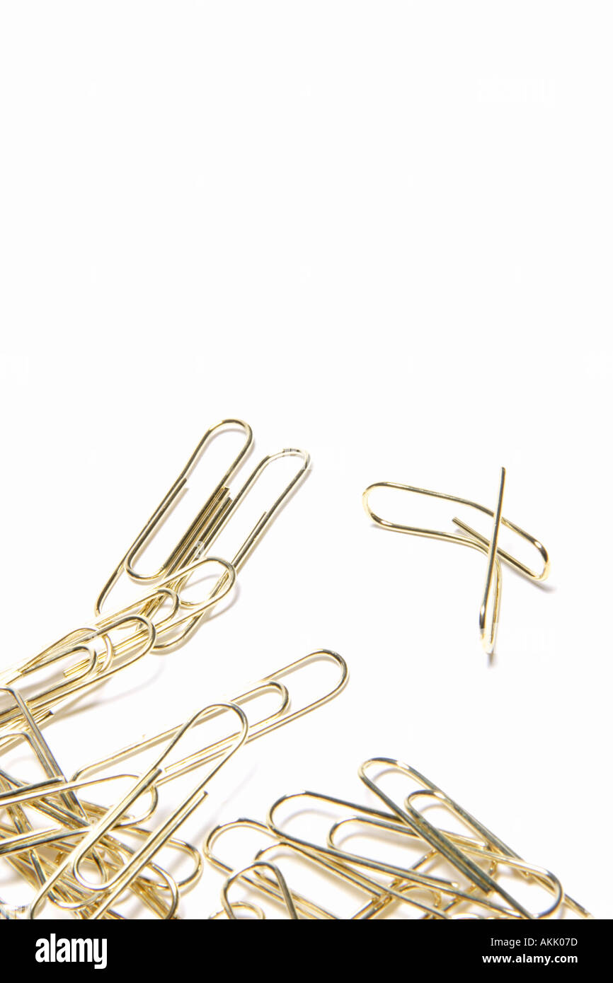 Gold coloured paperclips on white background Stock Photo - Alamy