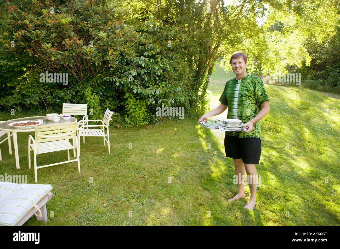 Man carrying tray to table in yard Stock Photo - Alamy