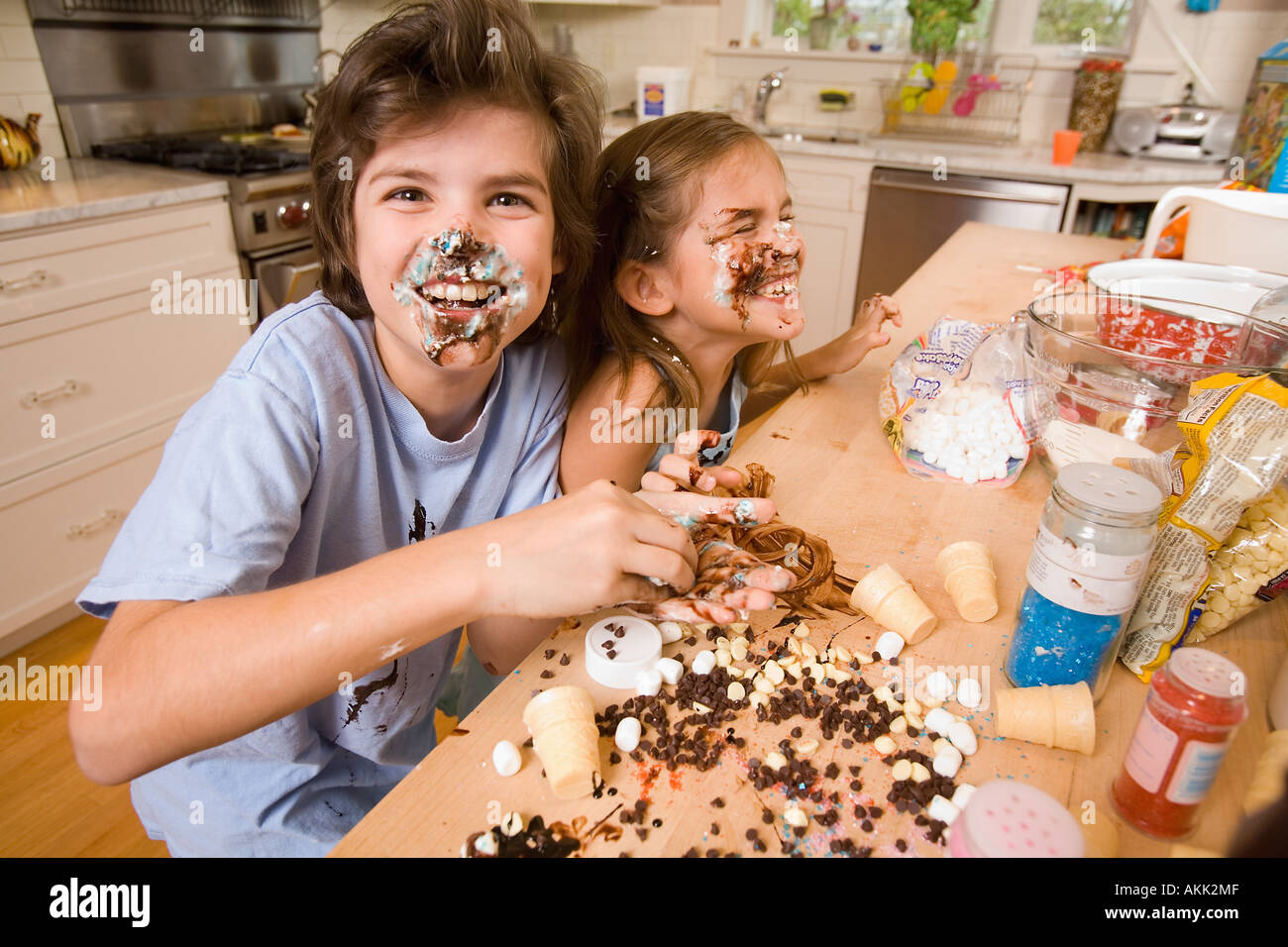 Portrait of boy and girl making mess in kitchen Stock Photo - Alamy