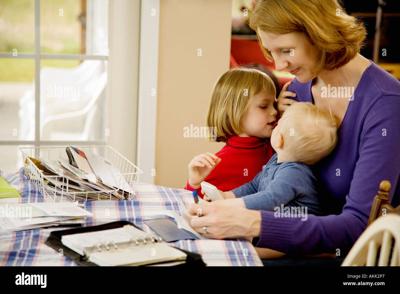 Mother holding children while writing Stock Photo - Alamy