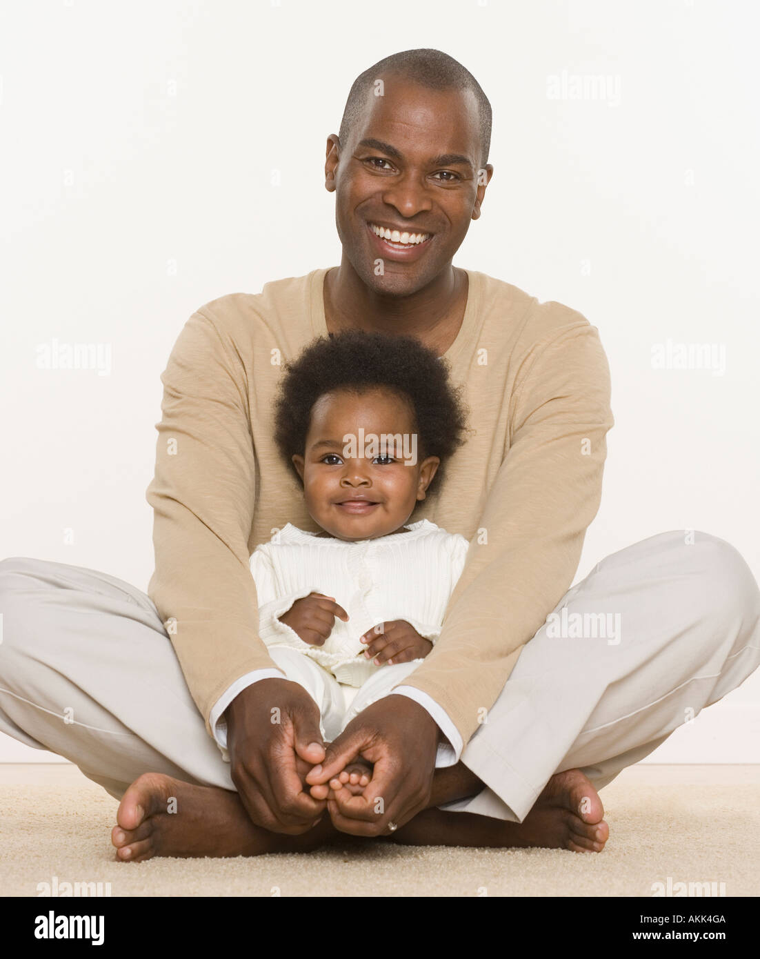 Father sitting cross legged while holding baby daughter Stock Photo - Alamy