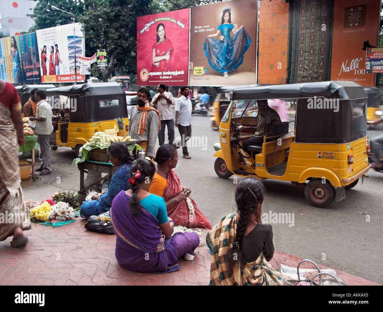 Busy street life women making flower garlands and men selling fruit as ...