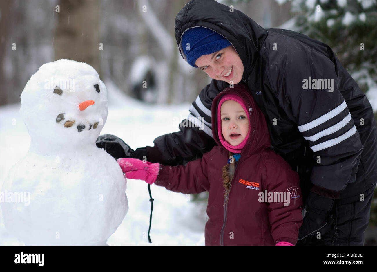 Two young girls making a snowman Stock Photo - Alamy