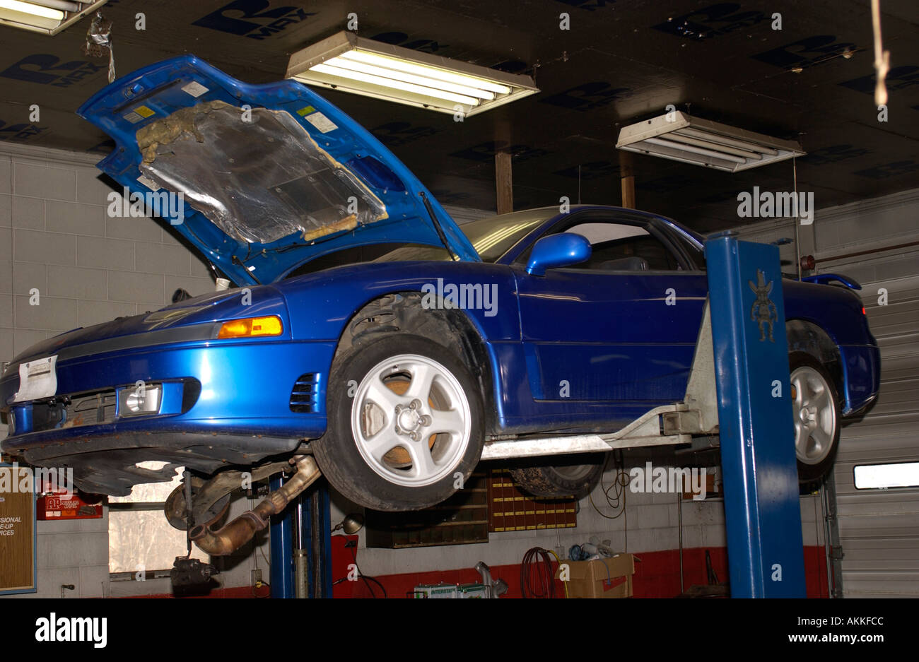 Blue mitsubishi 3000GT VR4 on lift at garage with transmissin hanging ...
