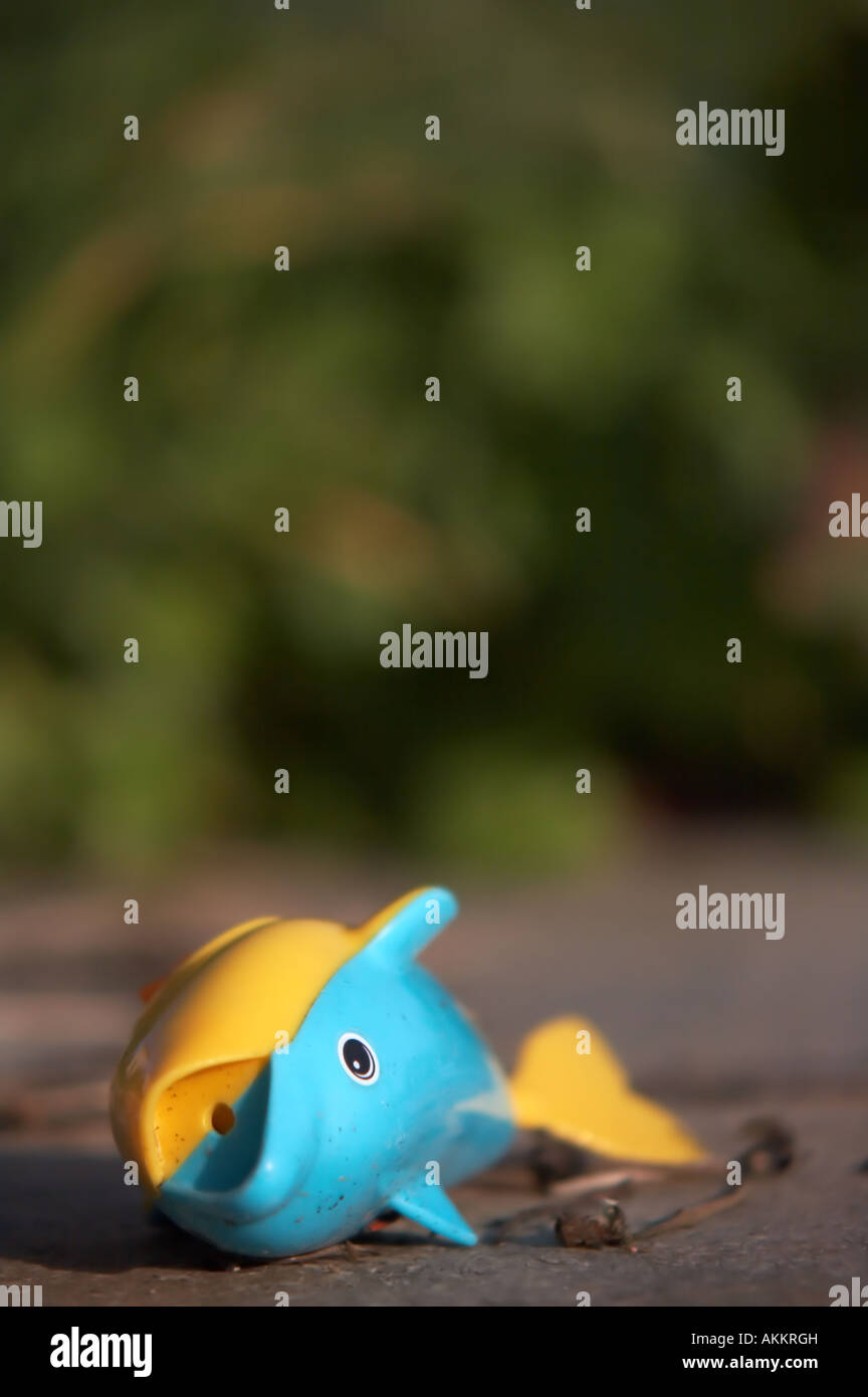 An abandoned plastic toy blue and yellow fish no a poolside in France ...