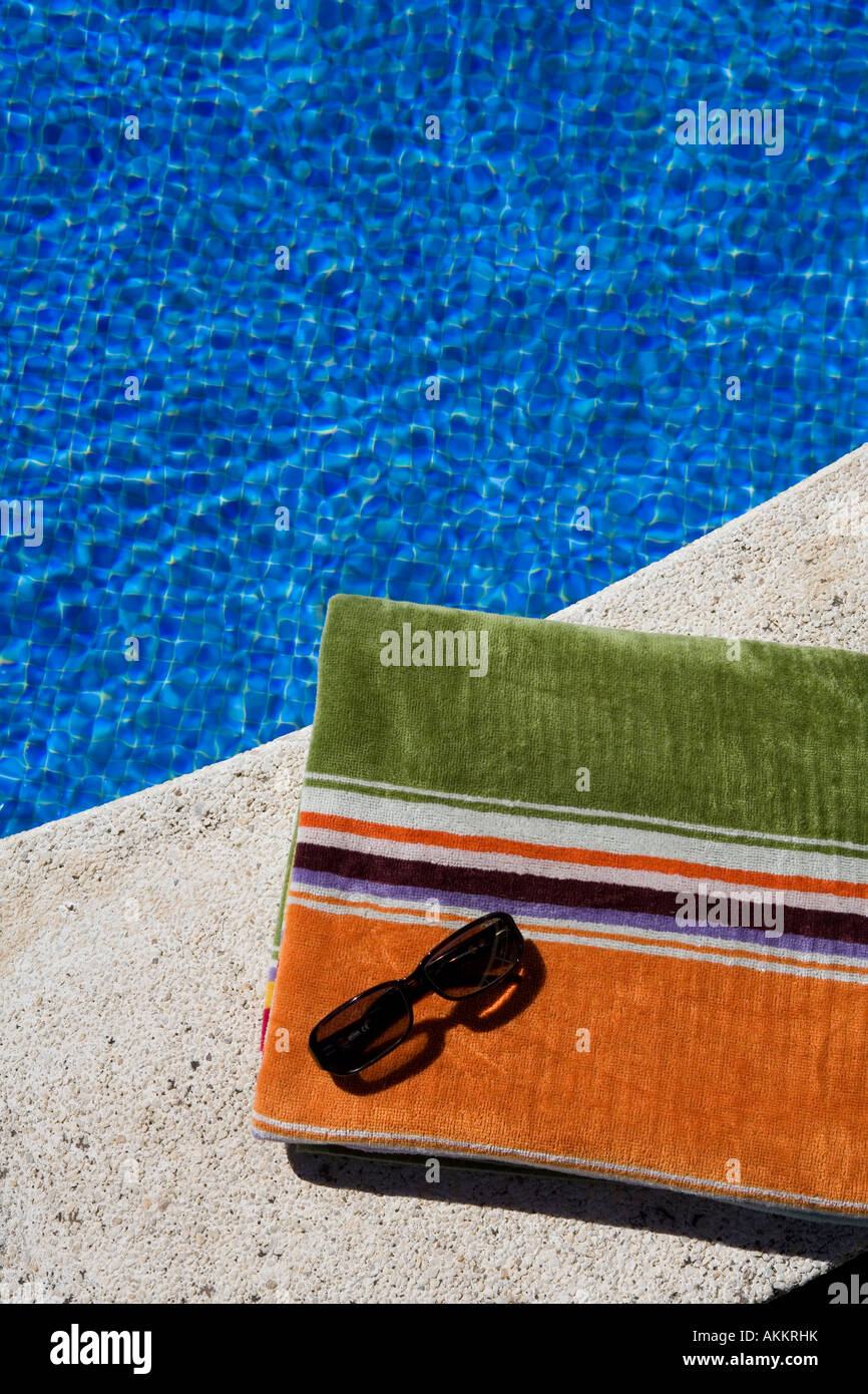 Folded beach towel and sunglasses by swimming pool Stock Photo - Alamy