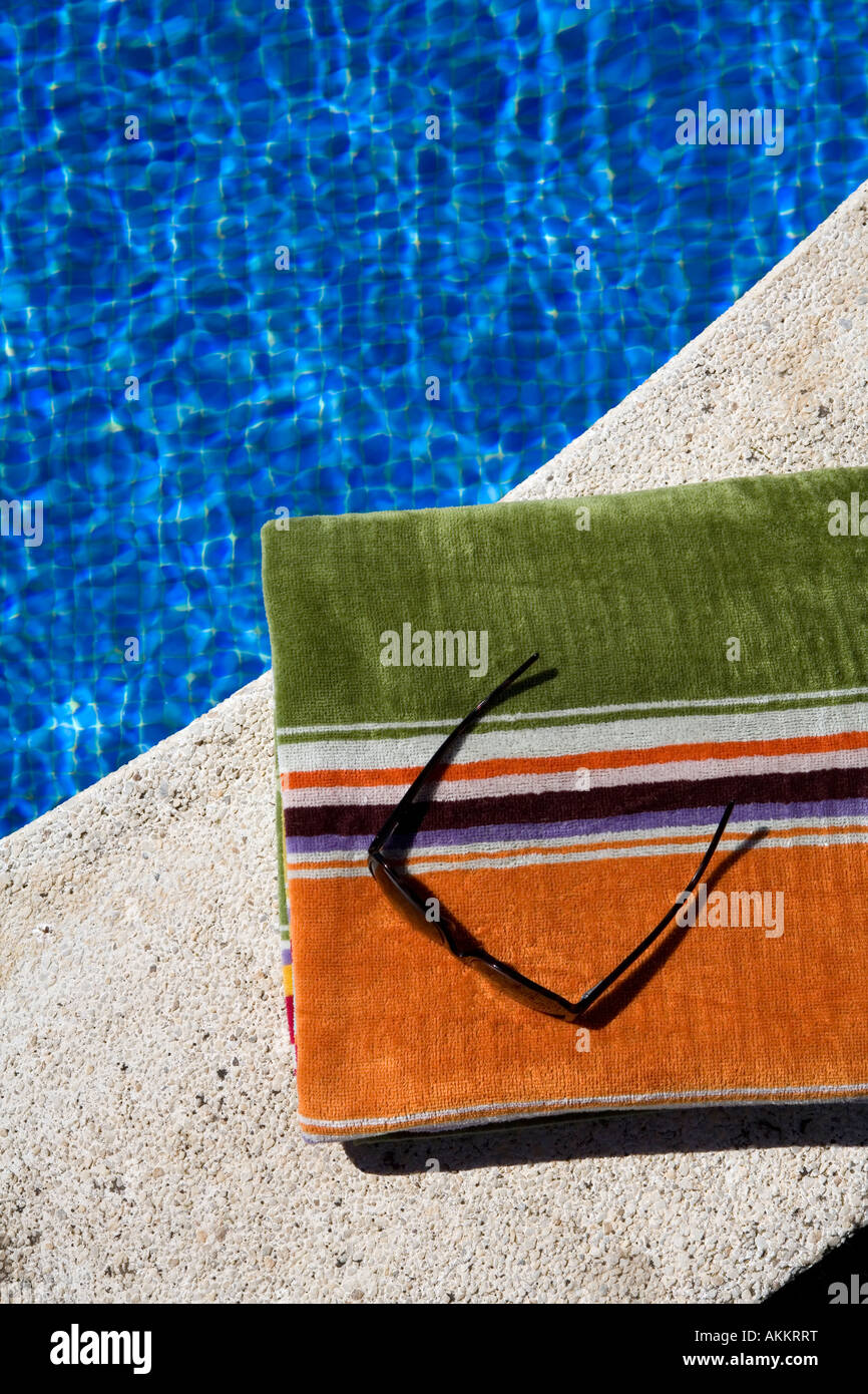 Folded beach towel and sunglasses by swimming pool Stock Photo - Alamy