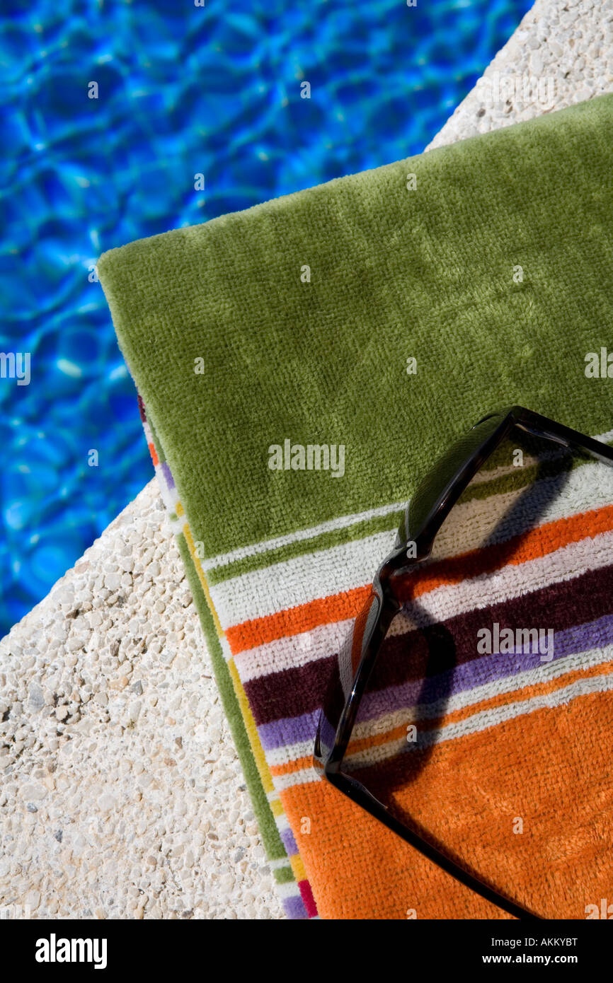 Folded beach towel and sunglasses by swimming pool Stock Photo - Alamy