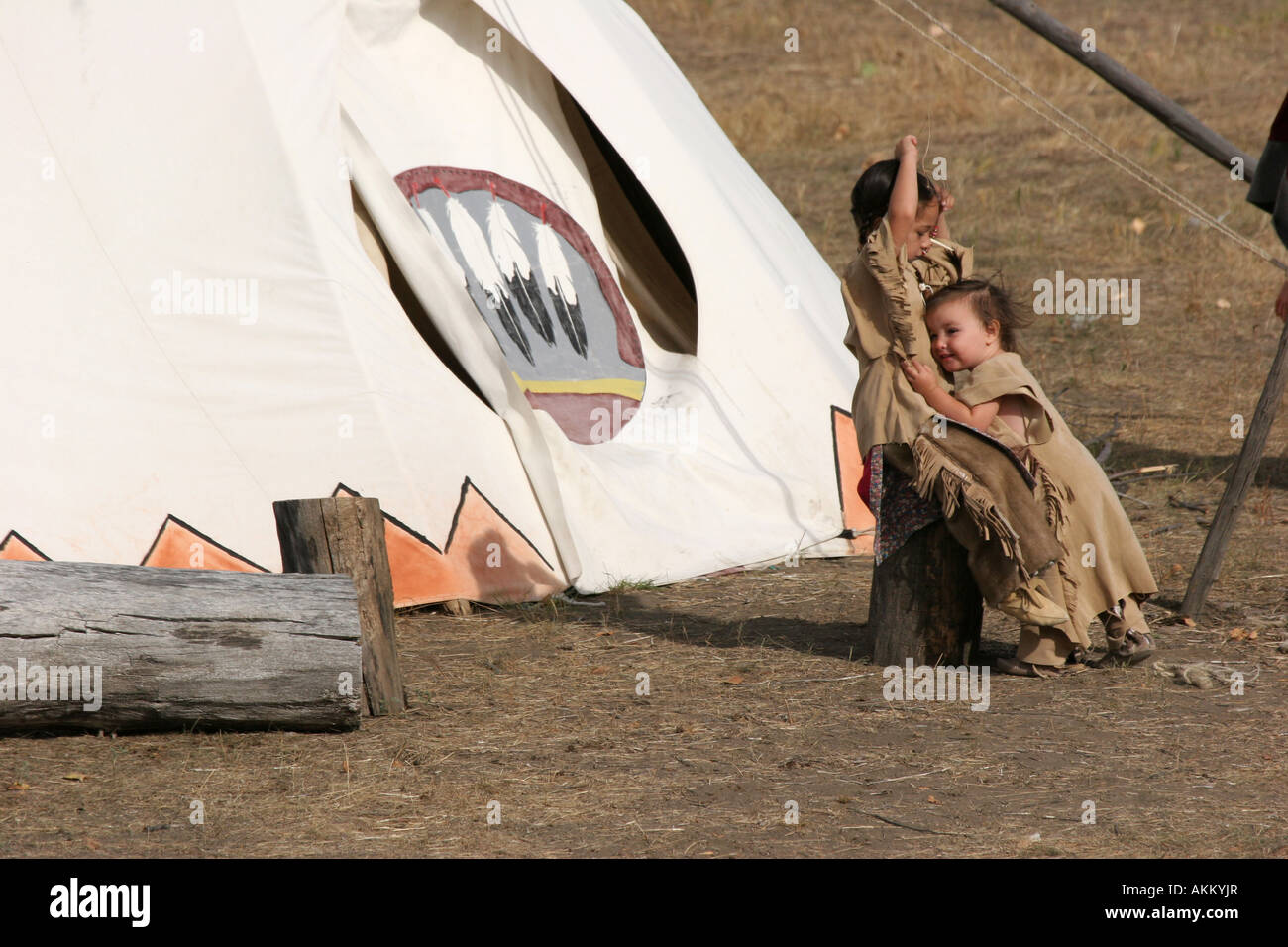 A young Native American Indian girl hugging her brother near their tipi ...
