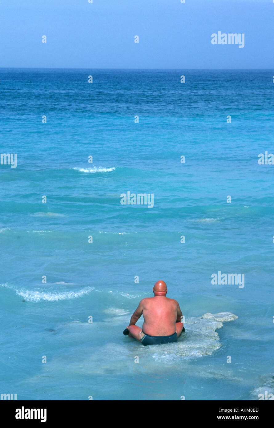 A man sunbathing in the mediterranean sea after taking a mud bath on ...