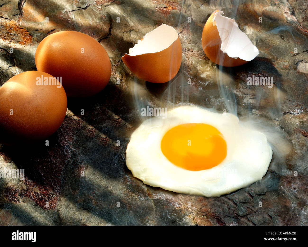 FRIED EGG COOKING AND STEAMING ON A PIECE OF STONE WITH CRACKED EGG ...