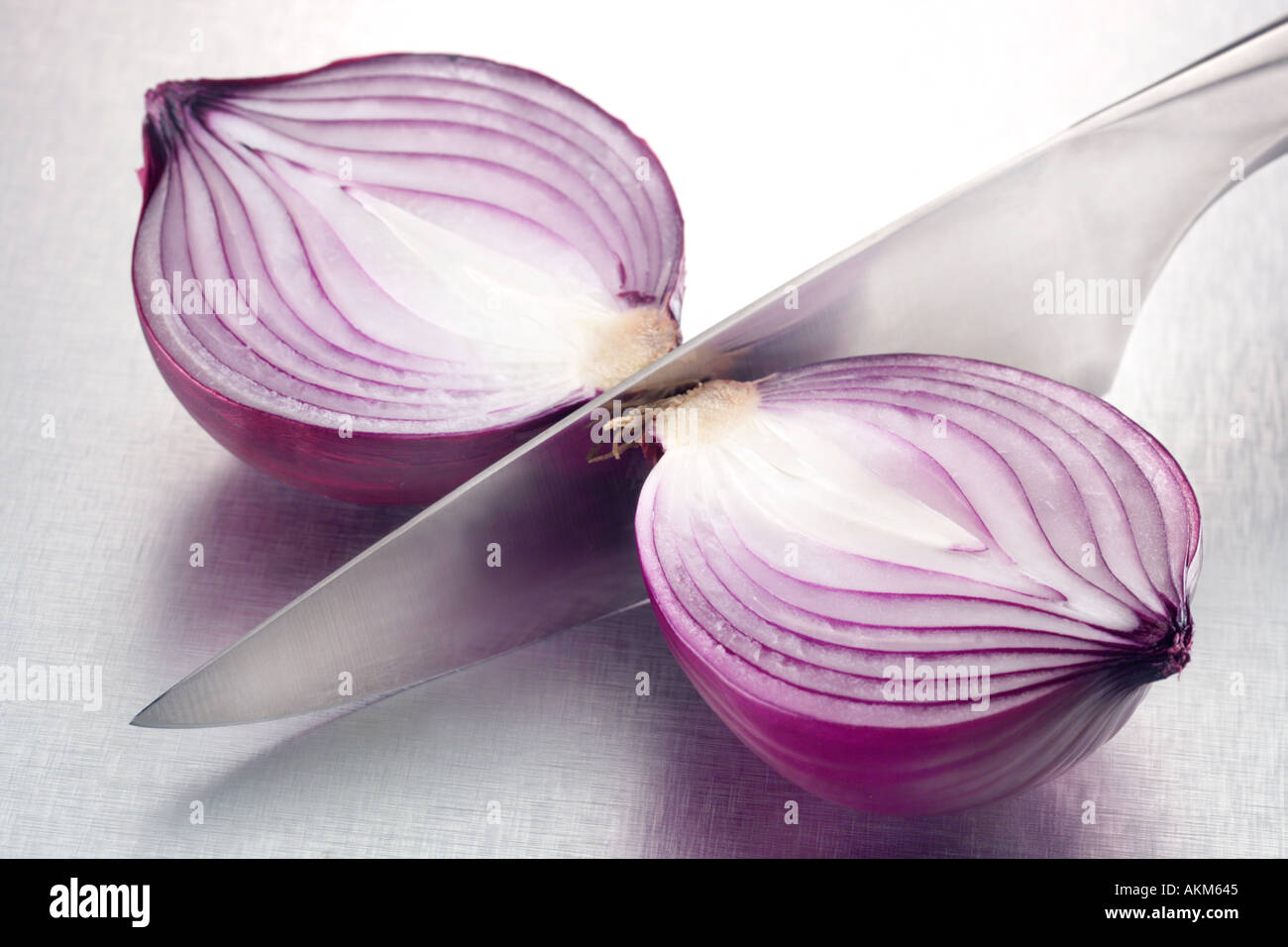 RED ONION BEING CUT IN HALF WITH LARGE KNIFE WHITE TABLETOP Stock Photo ...