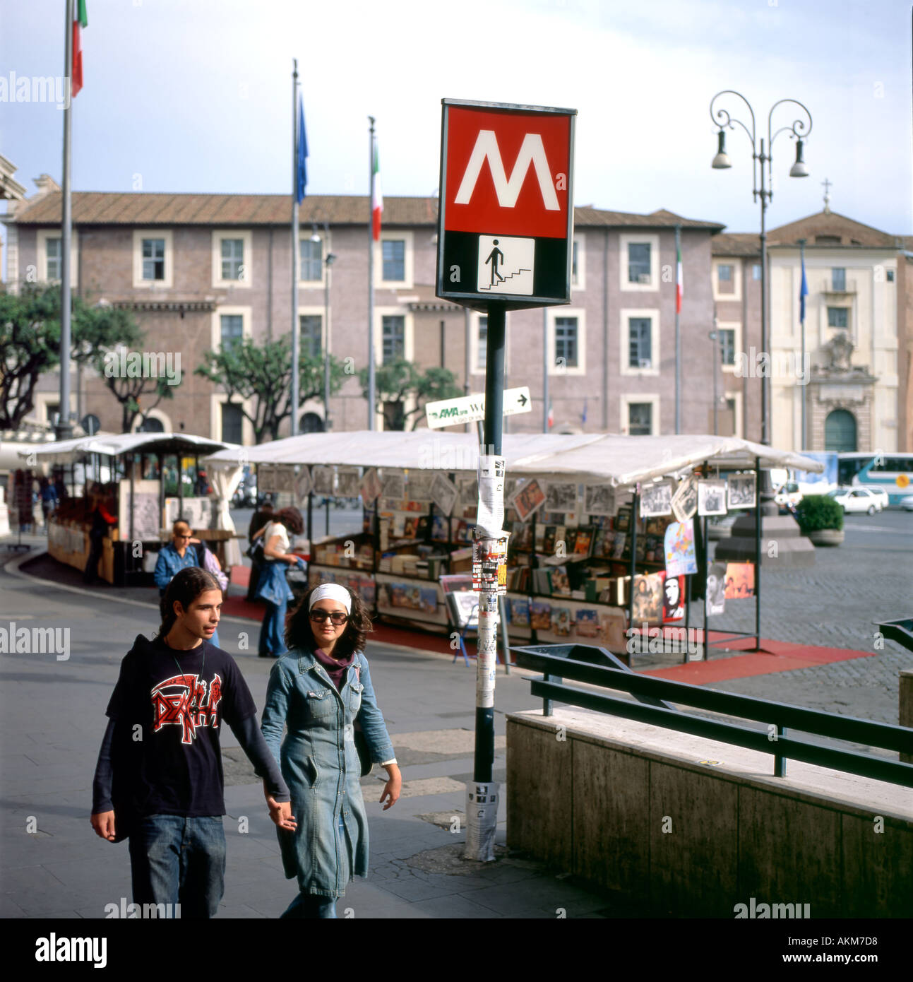 A red metro sign and a couple walking past the Piazza della Republica ...