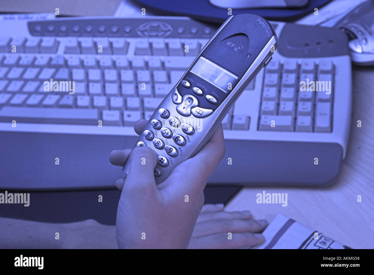 female using a phone whilst on a computer Stock Photo - Alamy