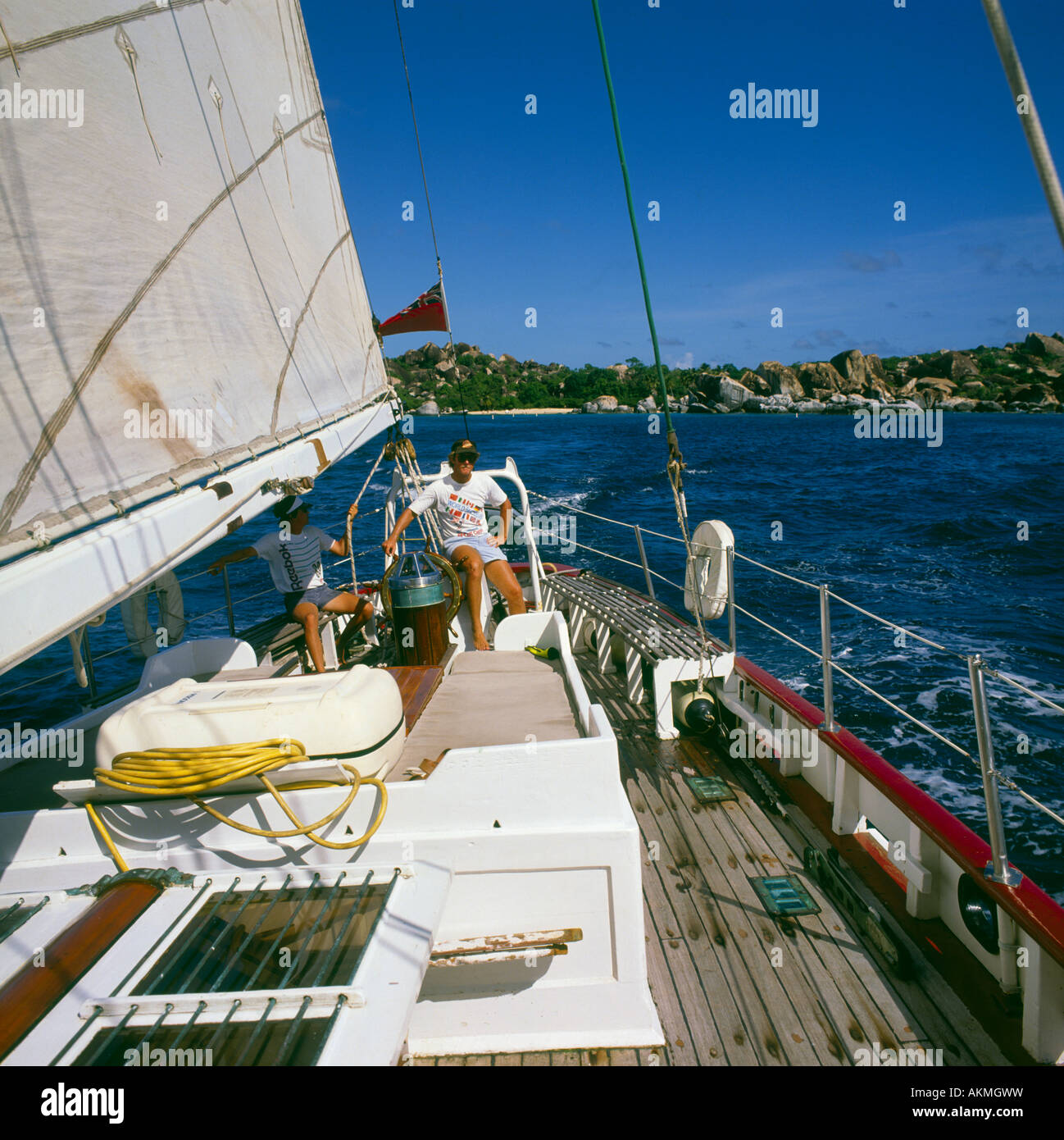 Captain in t shirt and shorts at tiller of large sailing yacht off ...
