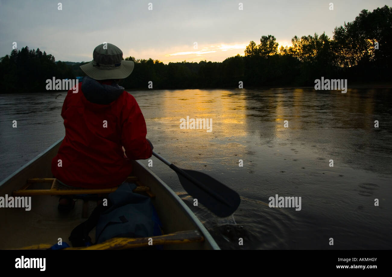 Female canoeist at dusk in the rain on the Riviere Rouge, Laurentian ...