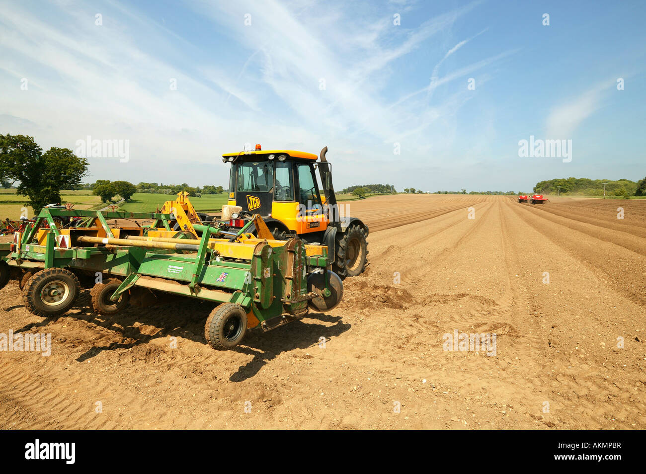 A tractor with seed sowing equipment planting carrots on farmland ...
