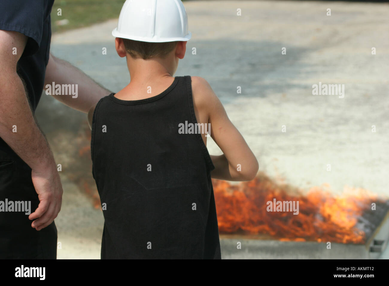 A boy learning how to use a fire extinguisher at a display with a fire ...